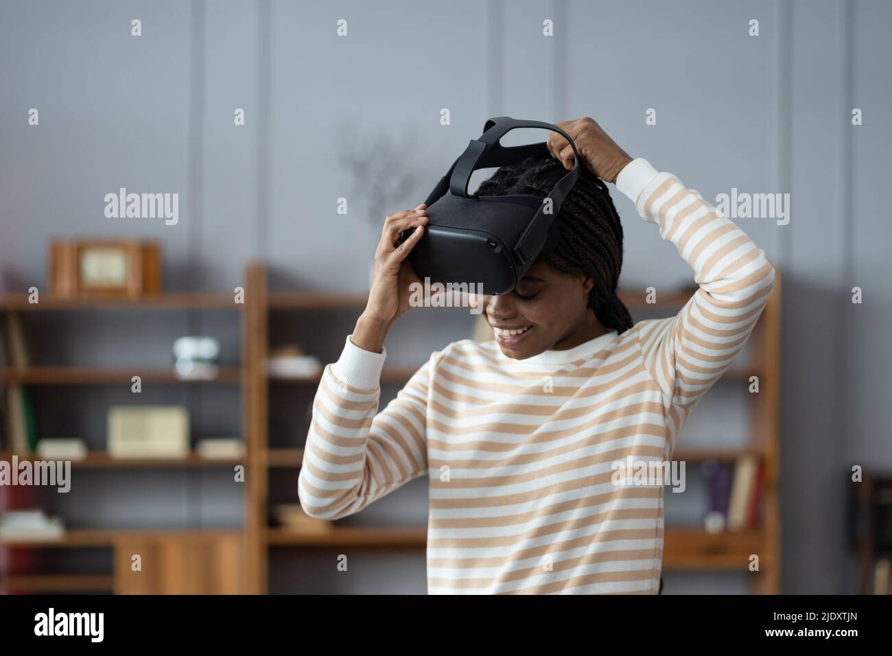 Inspired afro woman at home put on vr helmet to enjoy virtual reality ...