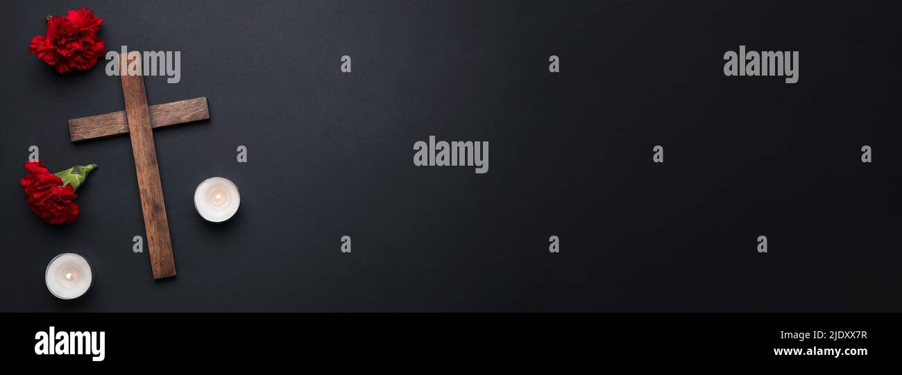 Wooden cross, carnation flowers and candles on dark background with ...