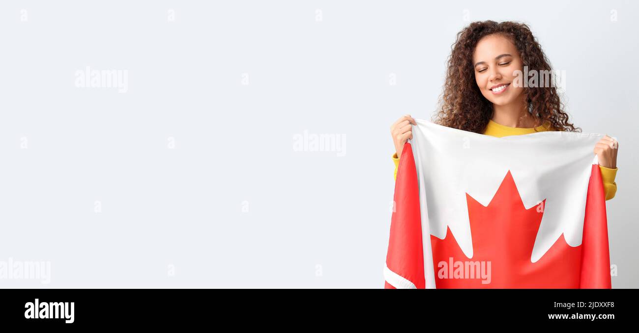 Beautiful young African-American woman with Canadian flag on light ...