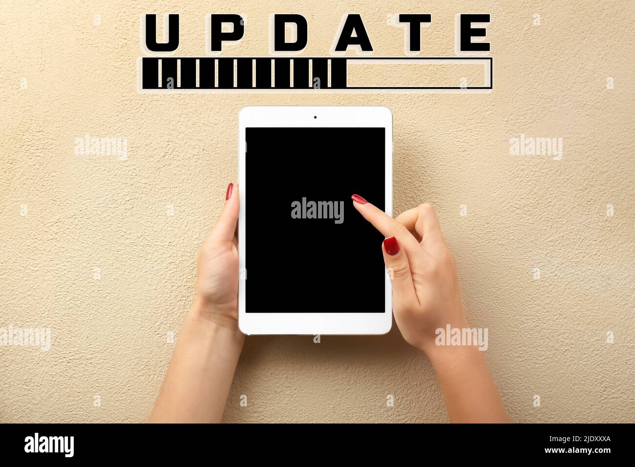 Hands with tablet computer, word UPDATE and status bar on beige ...