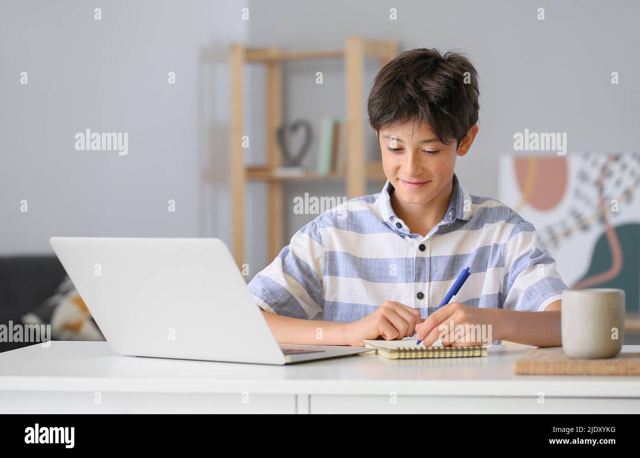 Teenage boy writing in notebook at home Stock Photo - Alamy