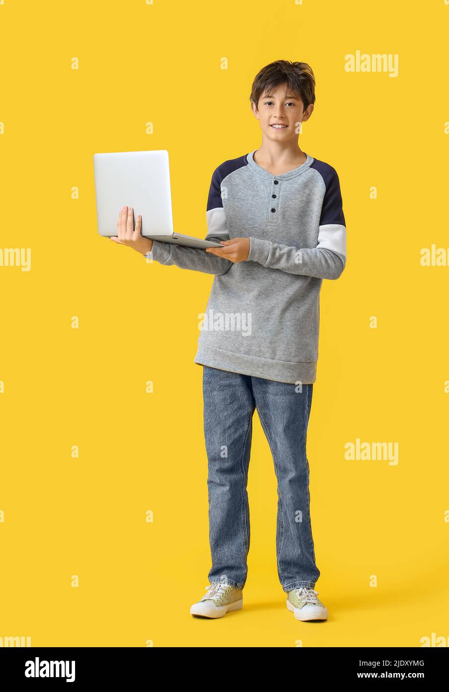 Teenage boy with laptop on yellow background Stock Photo - Alamy