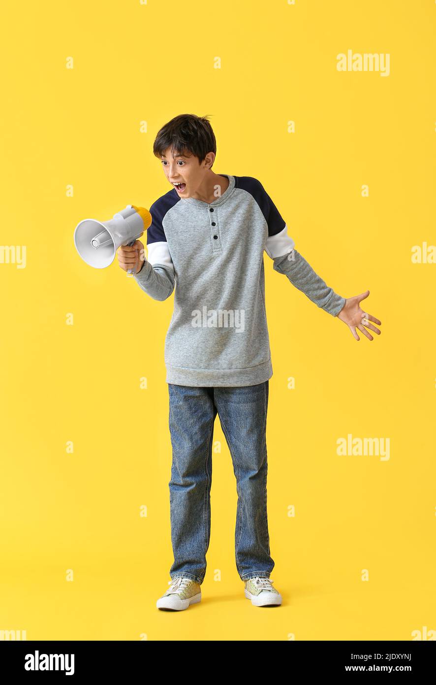 Teenage boy shouting into loudhailer on yellow background Stock Photo ...