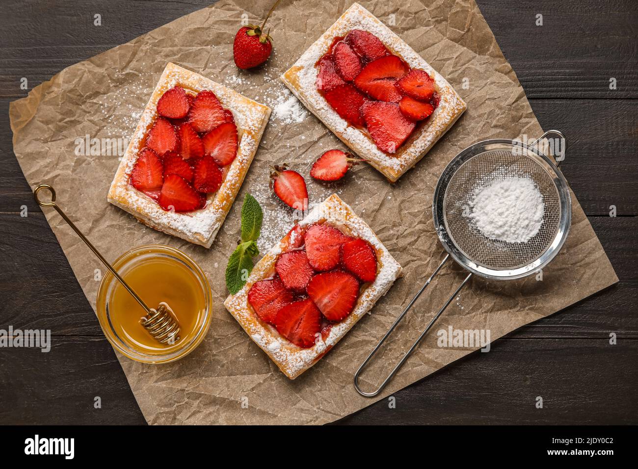 Delicious strawberry puff pastry, bowl with honey and sugar powder on ...