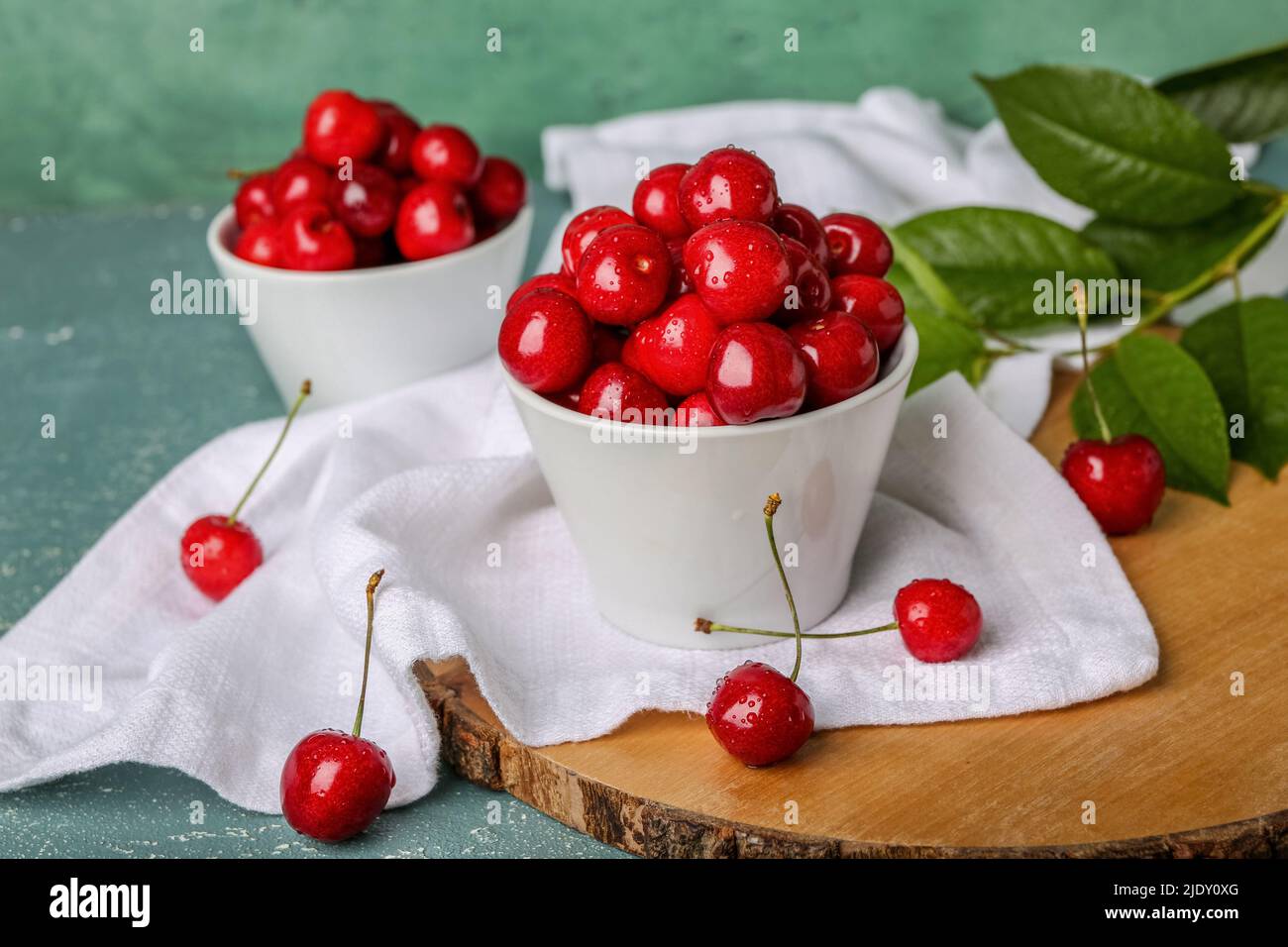 Wooden board with bowl of sweet cherries on color background Stock ...