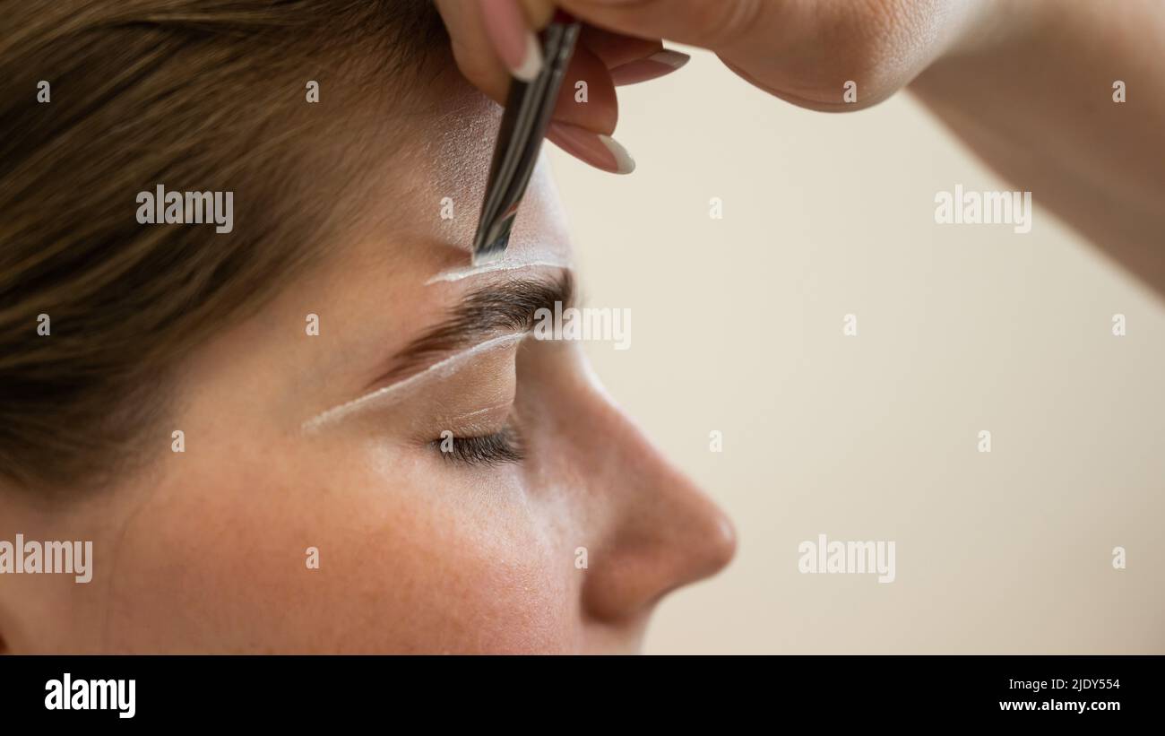 The master draws the shape of the eyebrows with white paint before ...