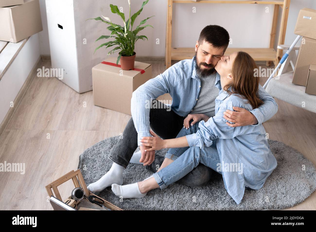 happy young couple sit on the floor in casual clothes and hugging woman ...