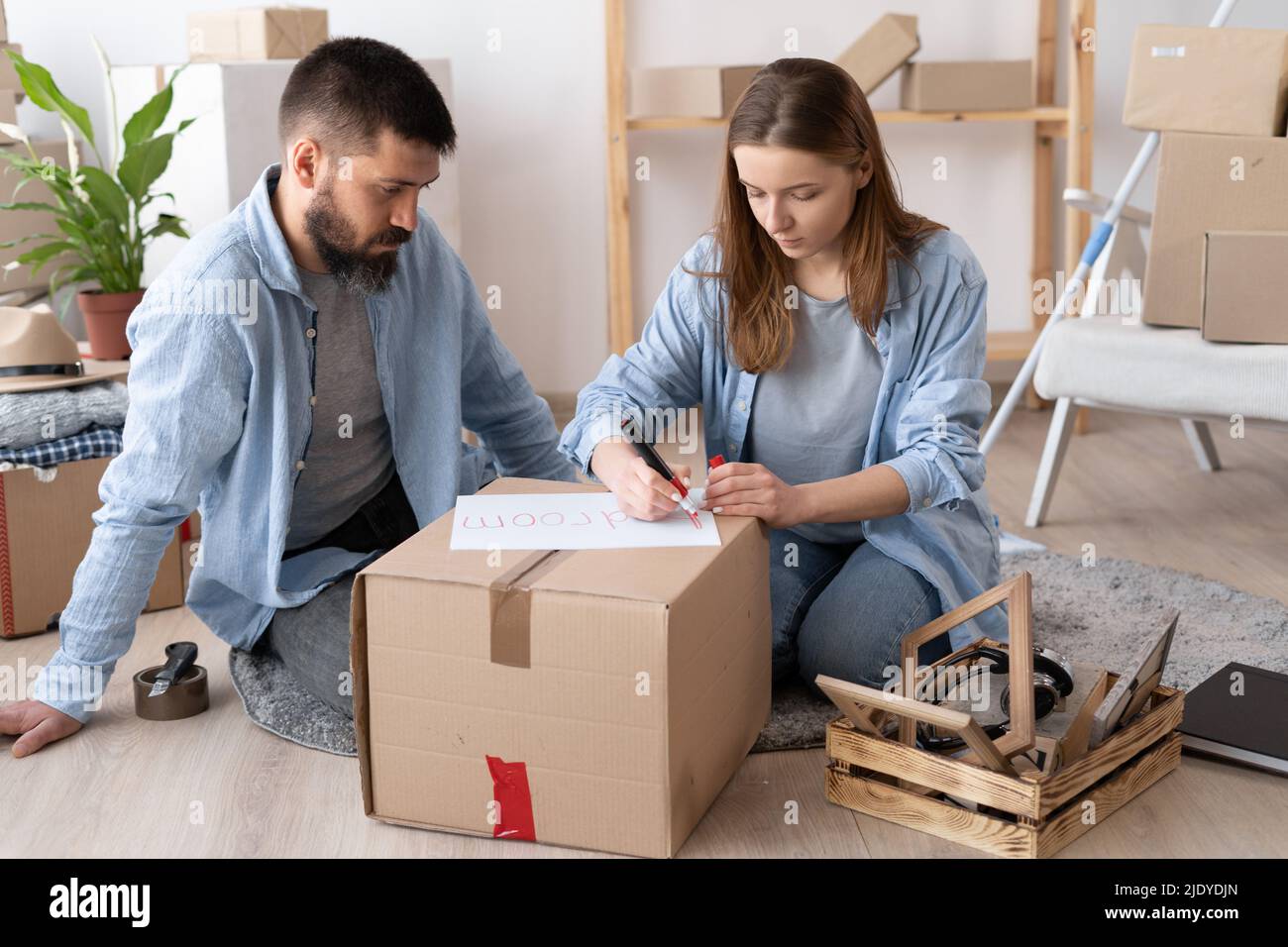 Moving Day And Relocation Concept Man And Woman Packing Cardboard
