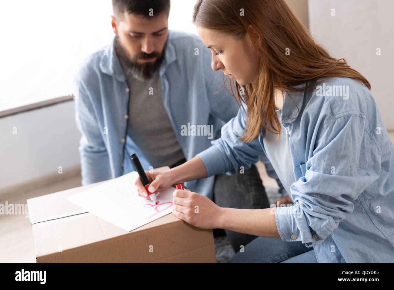 moving day and relocation concept, man and woman packing cardboard ...