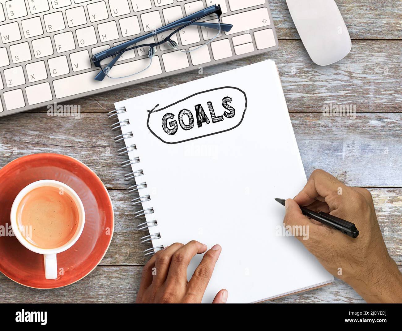 Top view with handwriting goals on notebook,keyboard,coffee and glasses ...