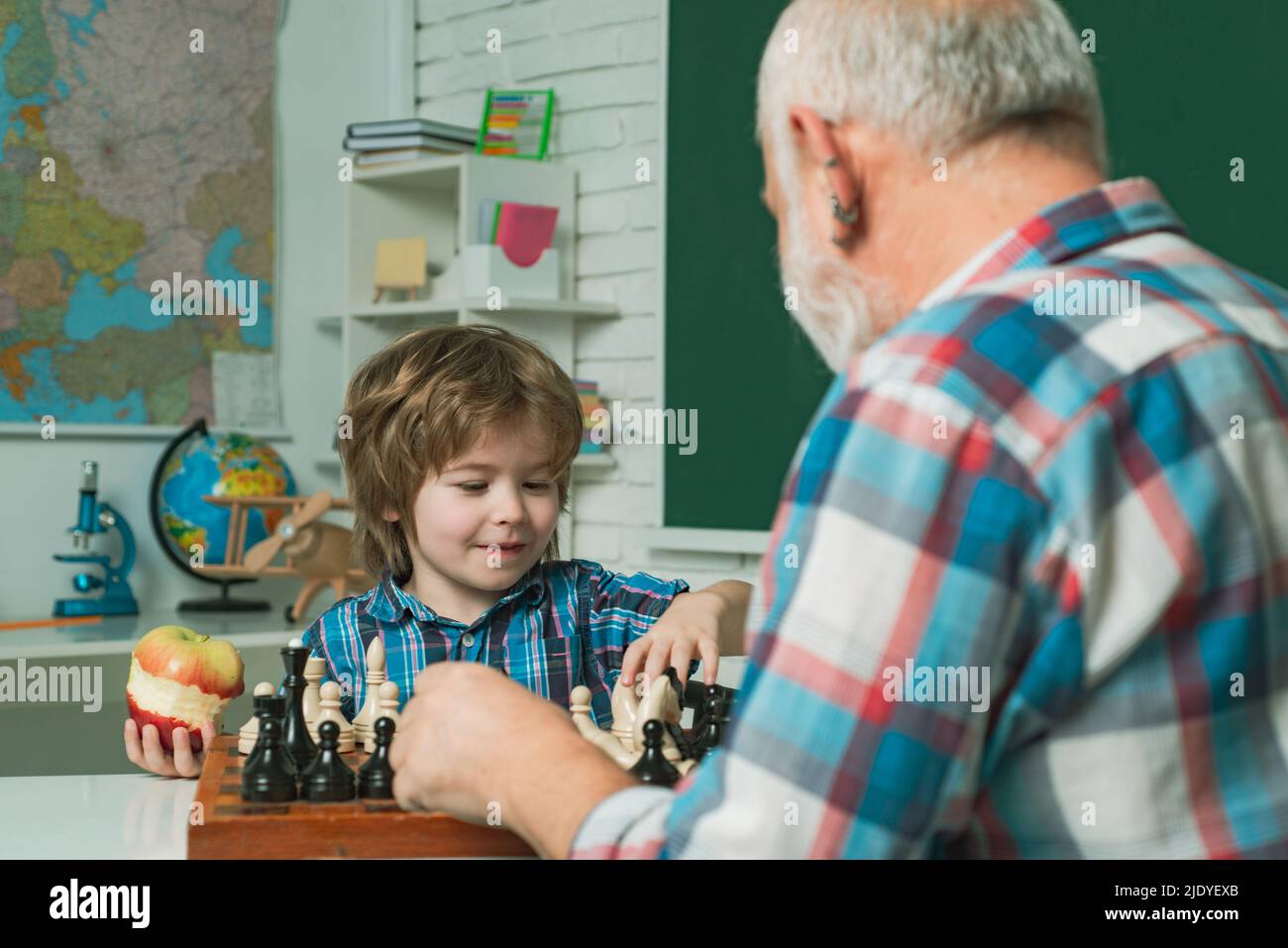 Grandfather and grandson child playing chess. Grandpa teaching grangson ...