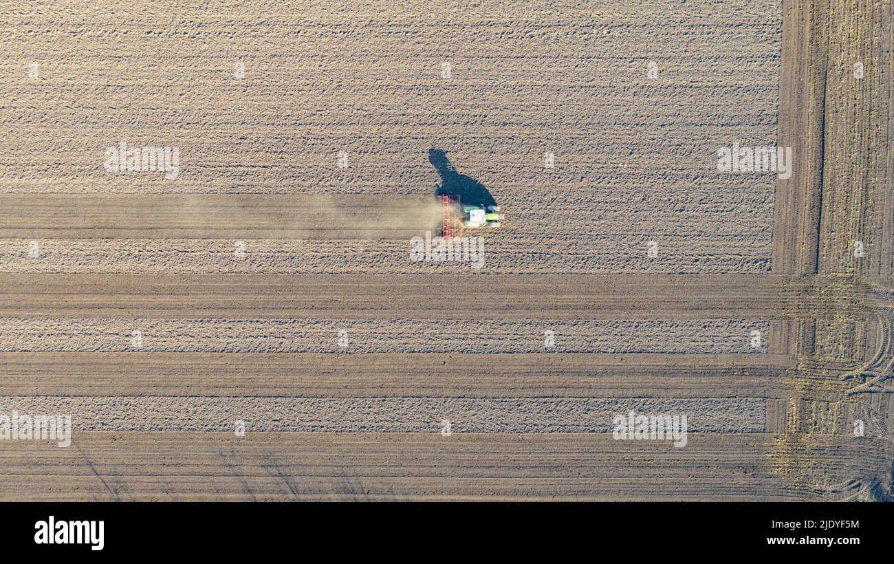 Above top view of tractor as pulling machine, harrowing arable field ...