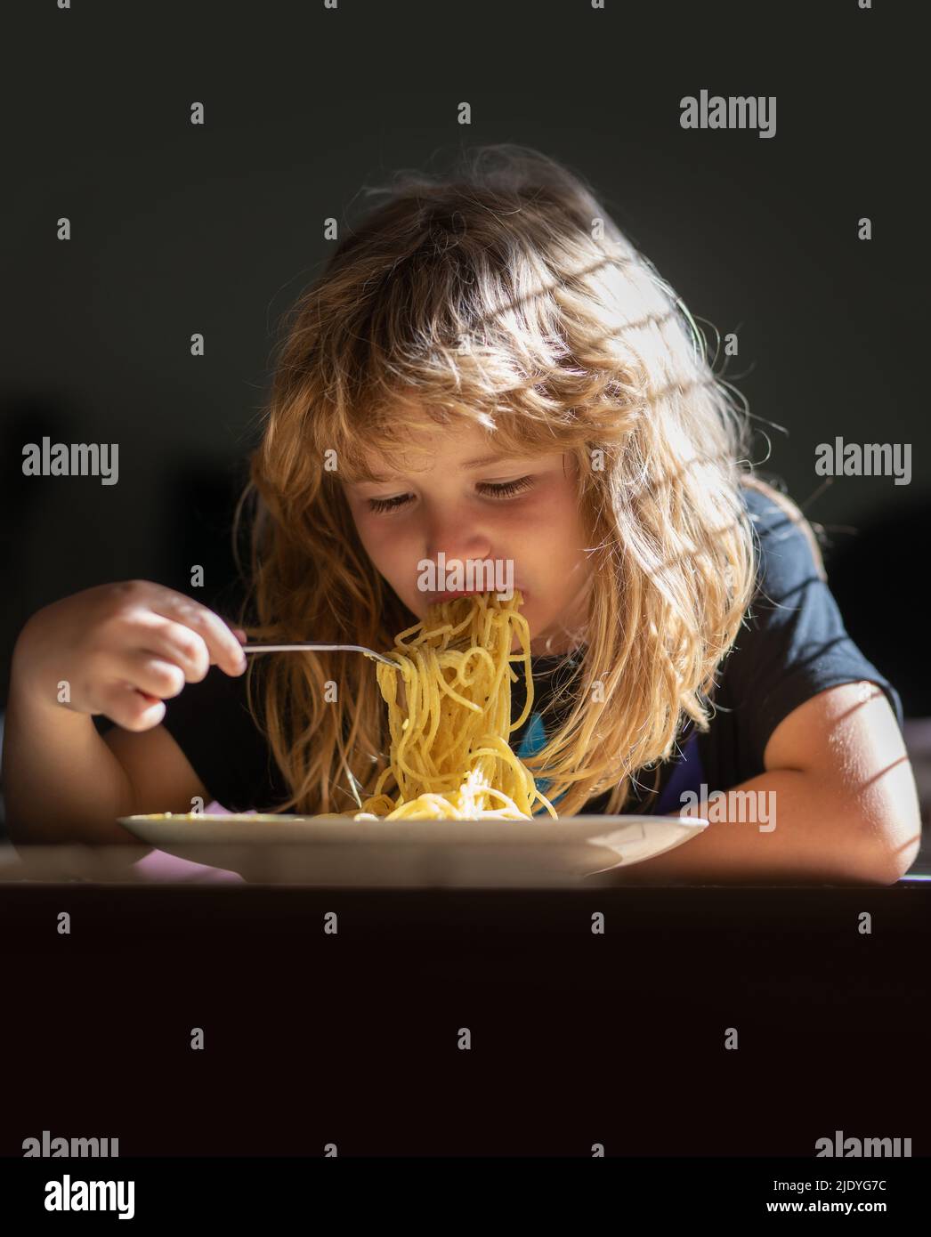 Little kid eating spaghetti in kitchen. Cute child eats food itself ...