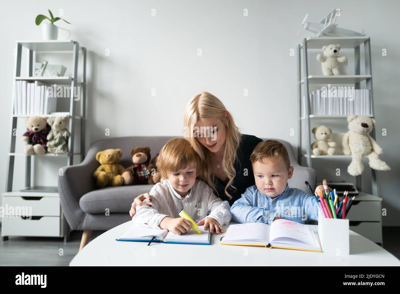 Teacher mom working with creative kids. Teacher helps school kids to ...