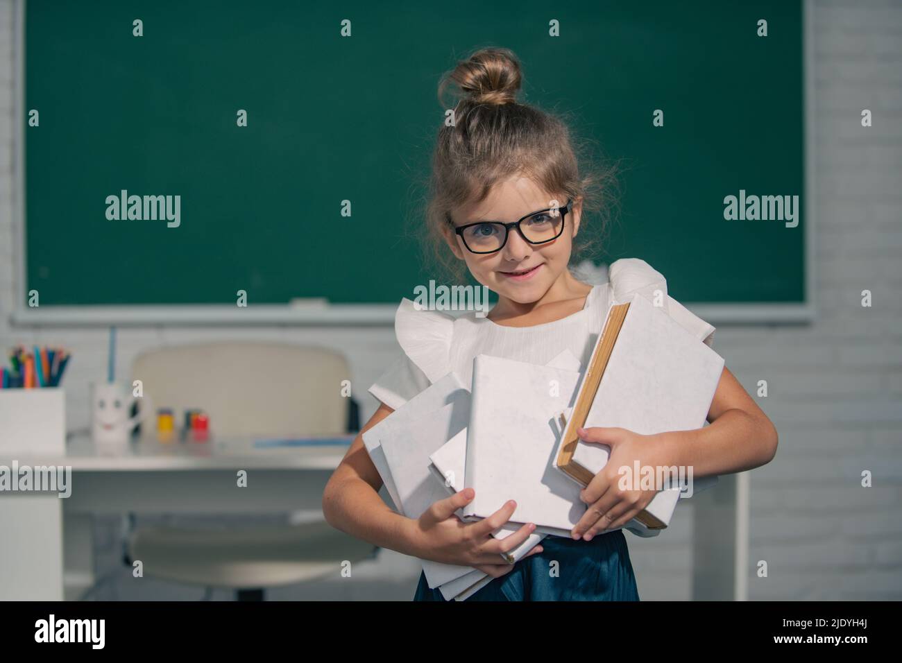 Portrait of funny pupil girl of primary school holds books. Elementary ...