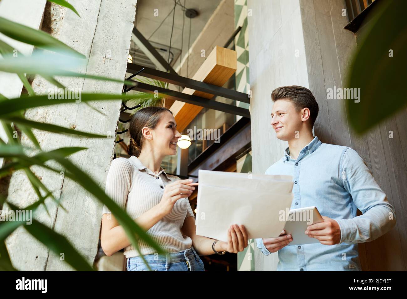 Below view of positive young designers standing in contemporary lobby ... Below view of positive young designers standing in contemporary lobby ...