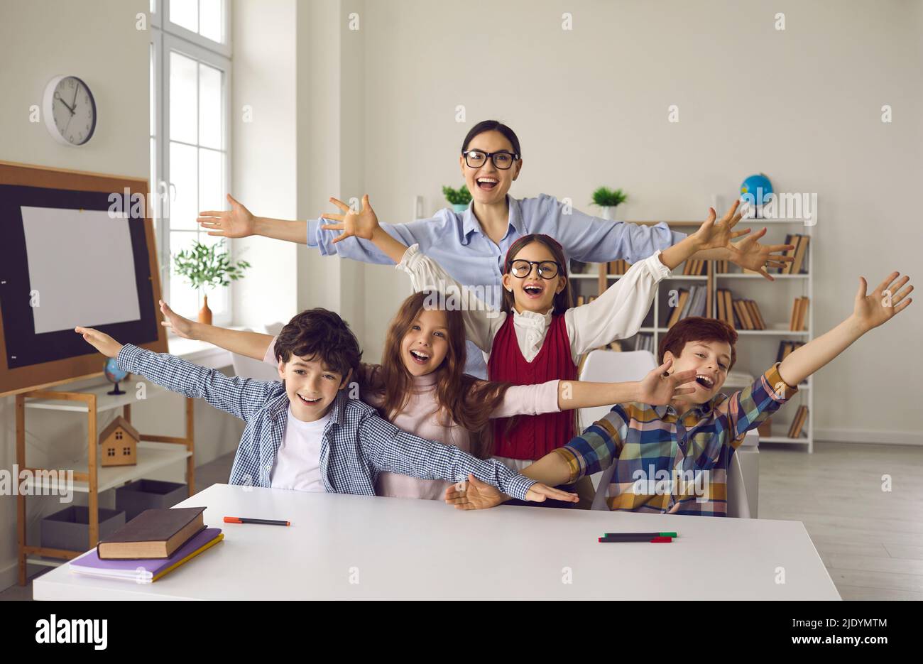 Happy teacher and group of her excited students laughing and having fun ...