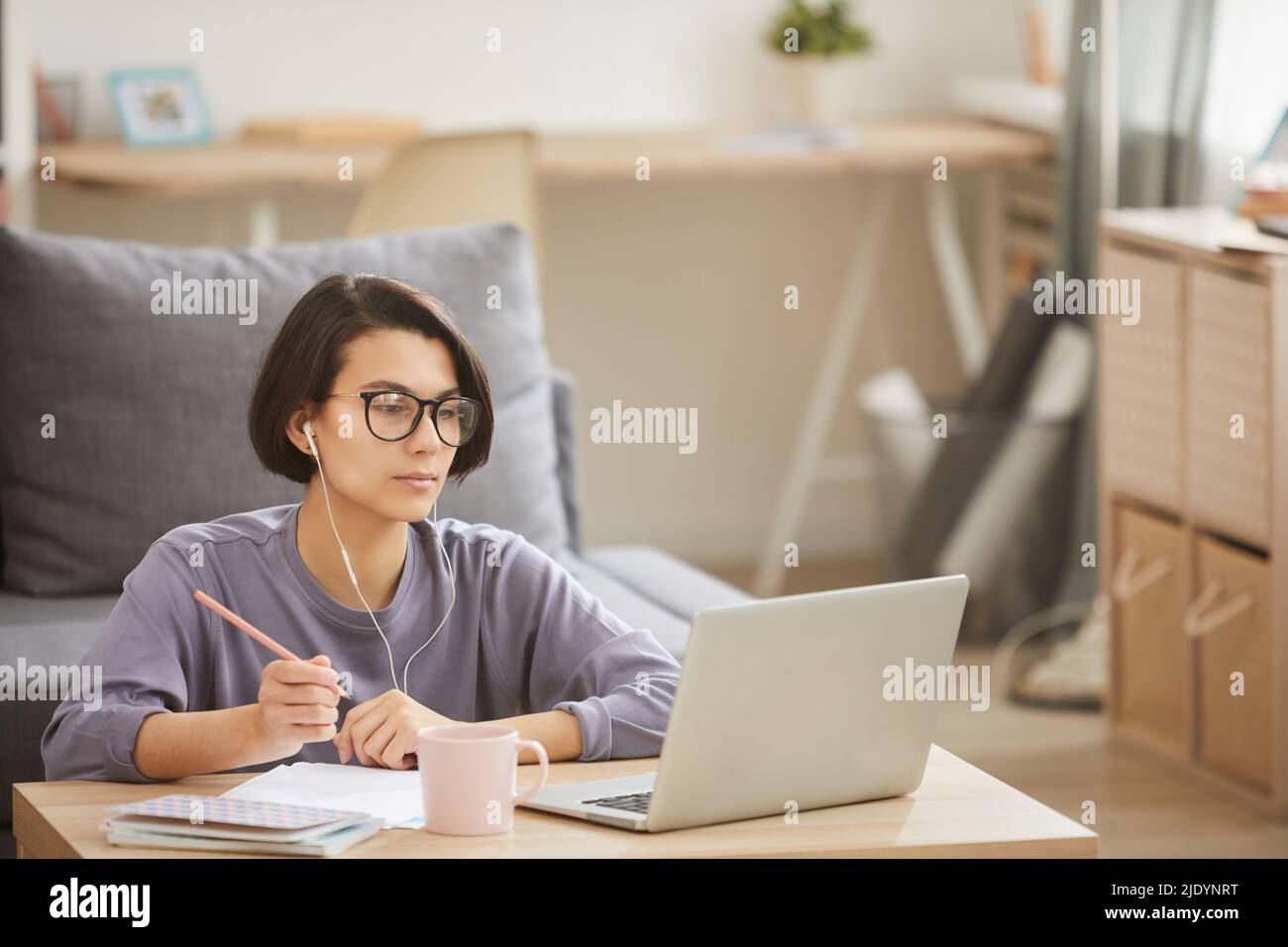 Concentrated young woman with short hair listening to audio in ... Concentrated young woman with short hair listening to audio in ...