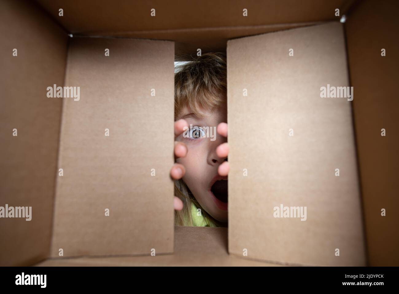 Child boy opening a carton box and looking inside, unpacking concept ...