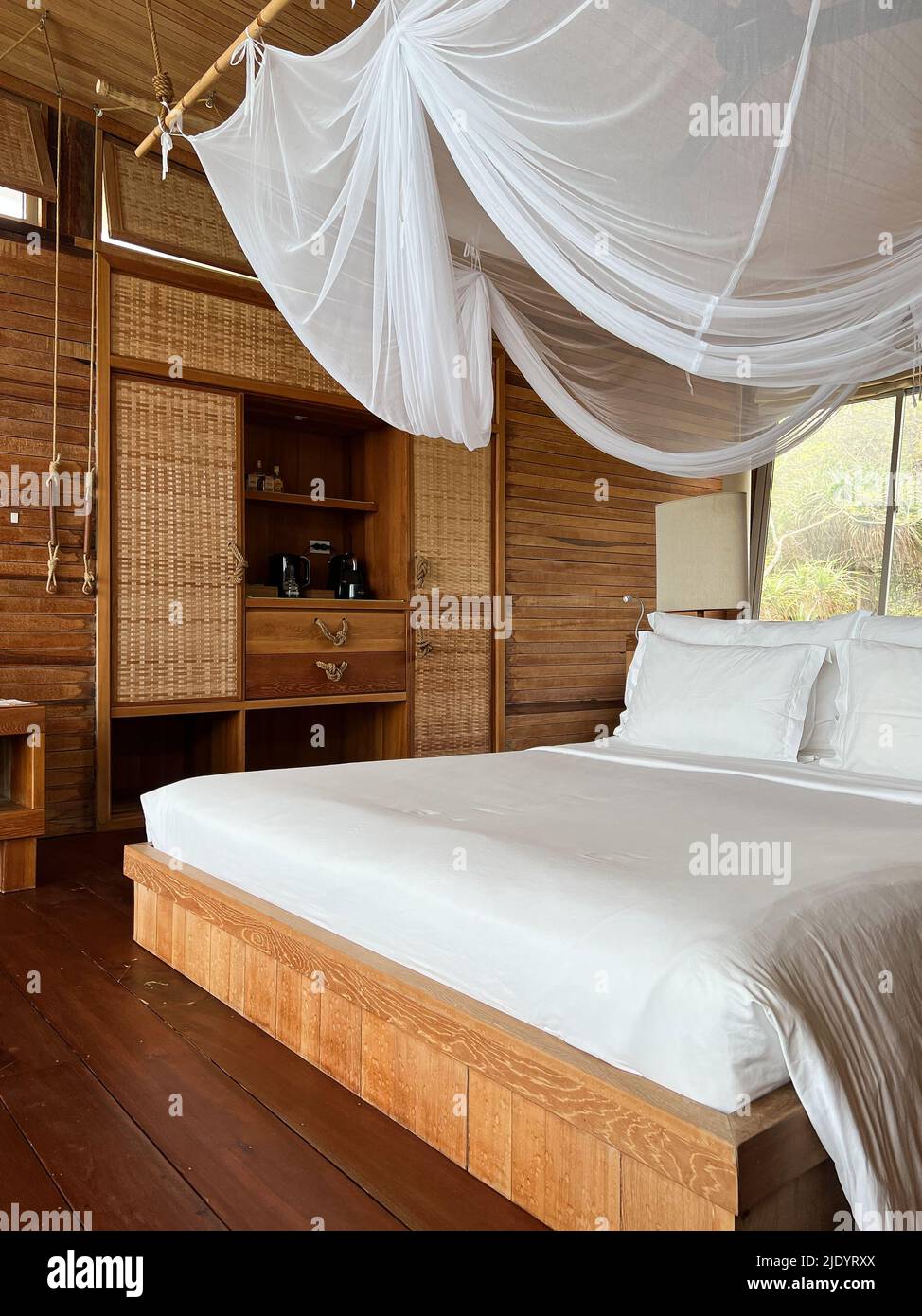 interior wooden tropical resort with bed, bedding and lighting decor on ...