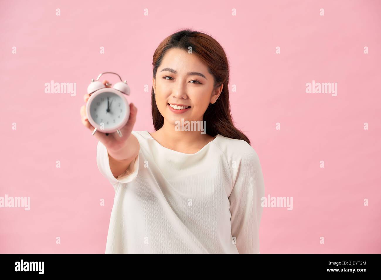 Happy young woman holding white alarm clock and waving hand isolated on ...