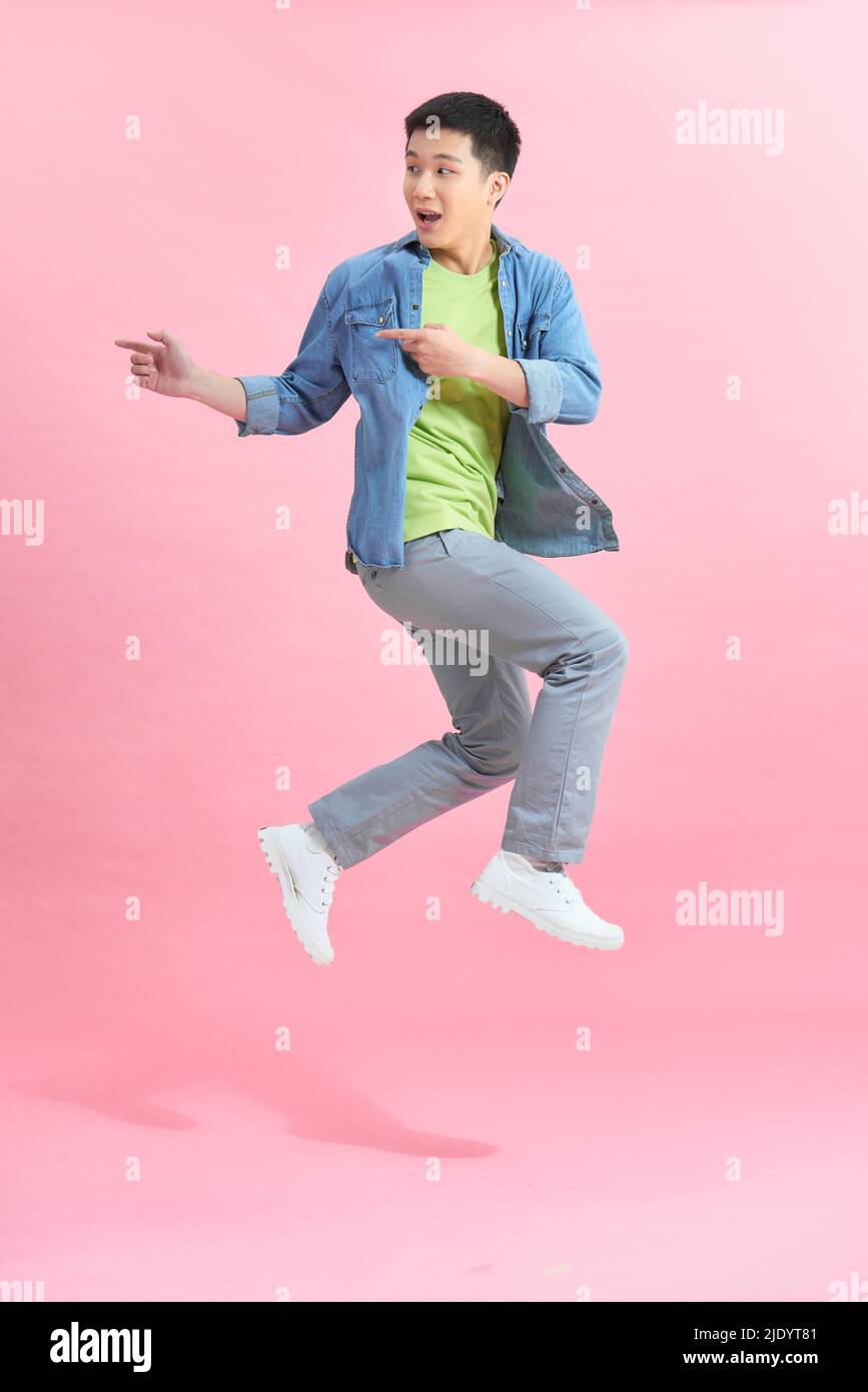 full length of excited young man with outstretched hands levitating on ...