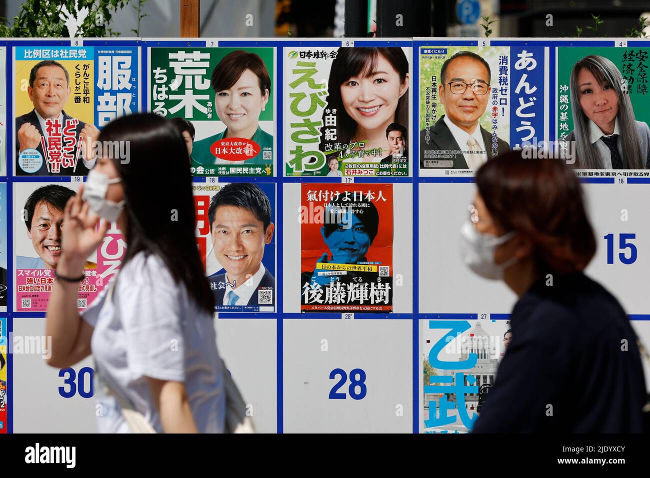 Tokyo, Japan. 24th June, 2022. Pedestrians walk past candidates ...