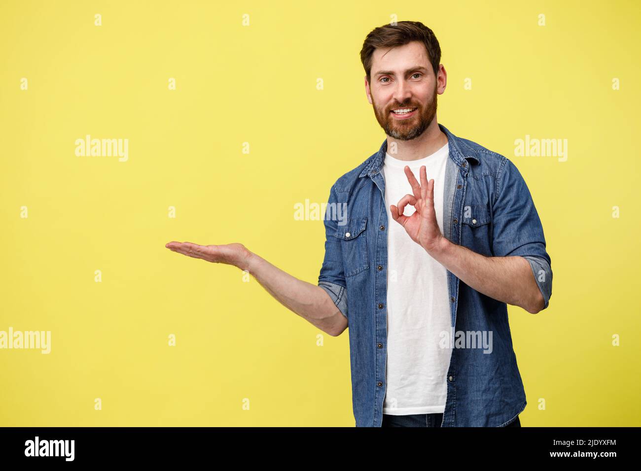 Positive man points his hand to side in empty place and shows sign okey ...