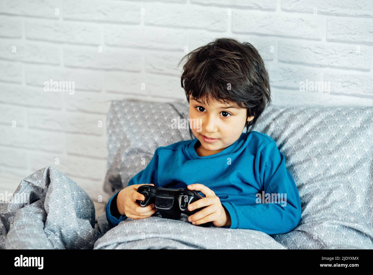 boy playing video games with joystick game console sitting on sofa in ...