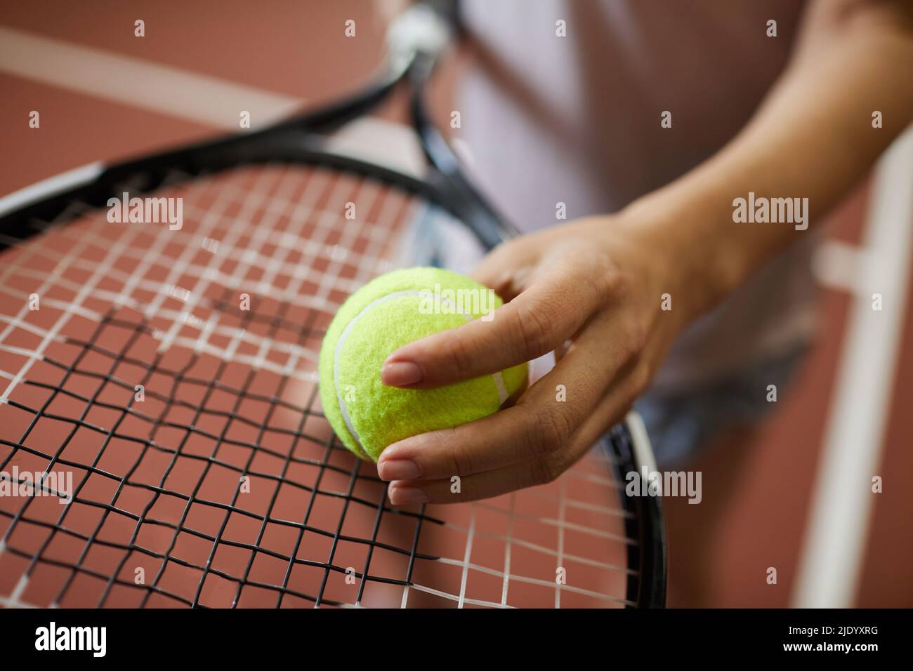 Close-up of unrecognizable woman putting tennis ball on racket while ...