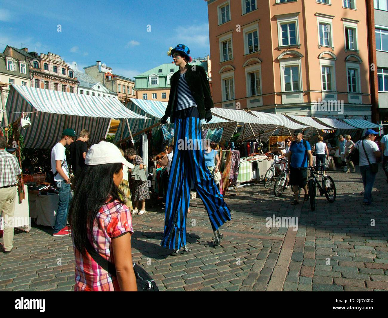 Street trading on the Dome Square in Riga. A man on stilts attracts ...
