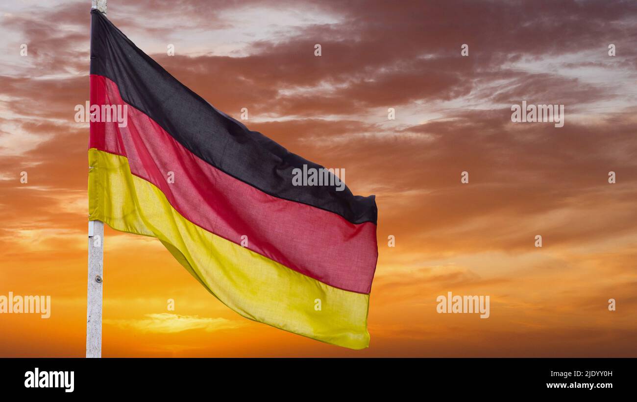 The official flag of Germany waving on a blue sky background ...