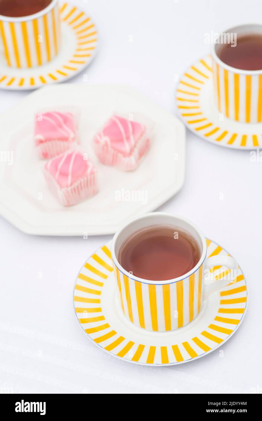 Afternoon tea. Black tea served in bright yellow striped cups and ...