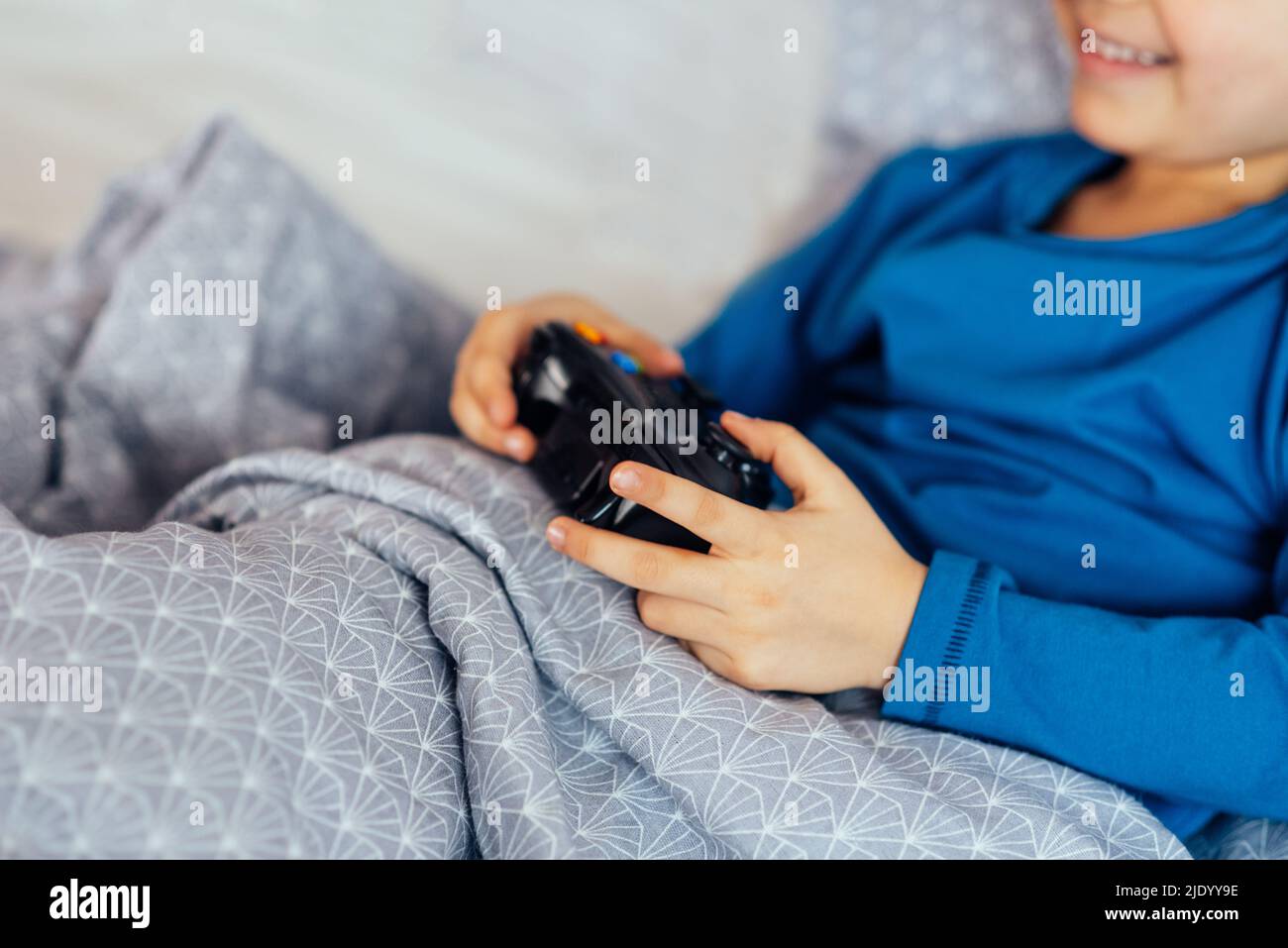 boy playing video games with joystick game console sitting on sofa in ...