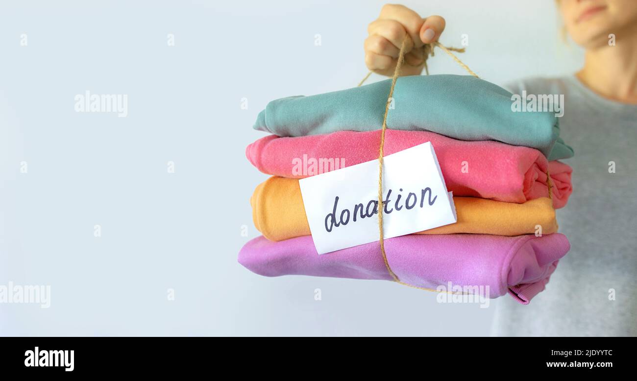 Women's hand give a stack of clothes to children's hands. Helping the ...