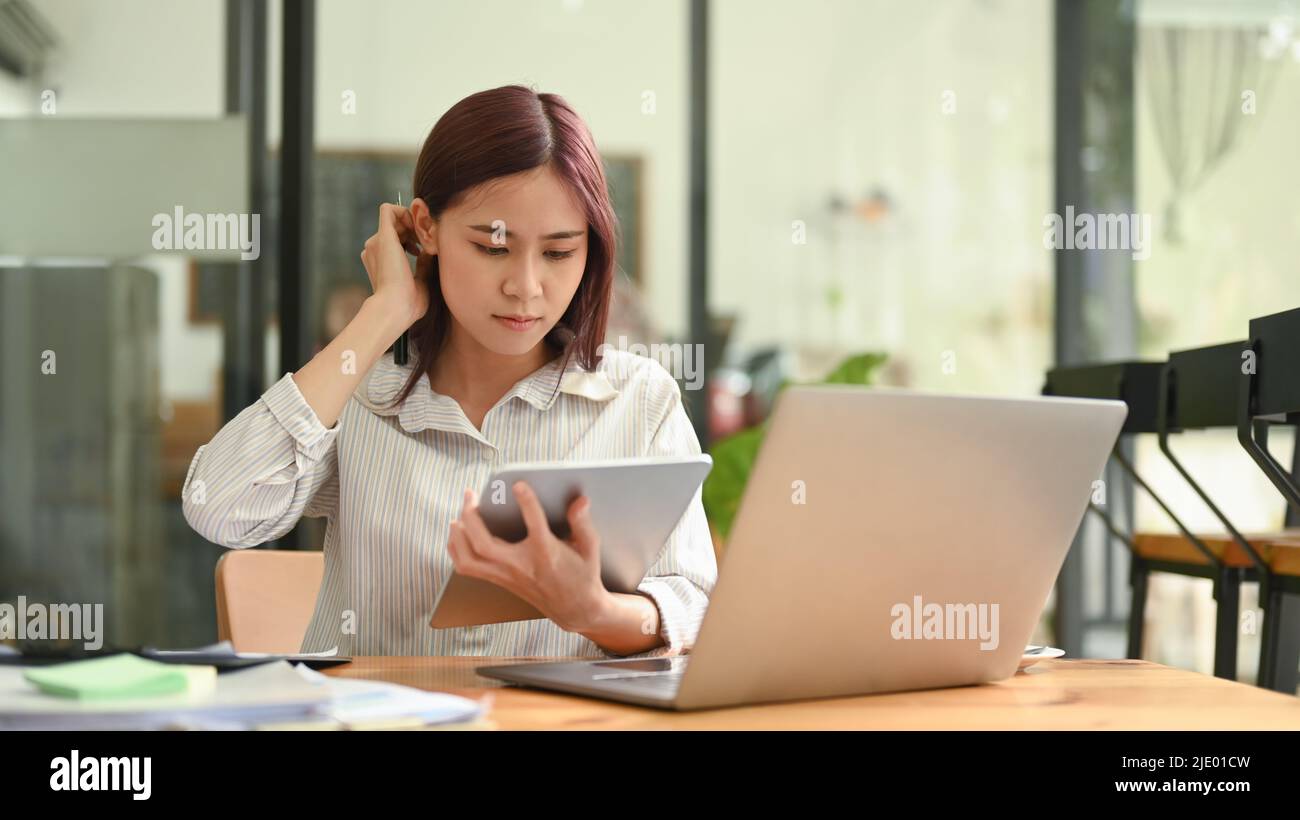 Focused asian female office worker sitting front of laptop computer and ...