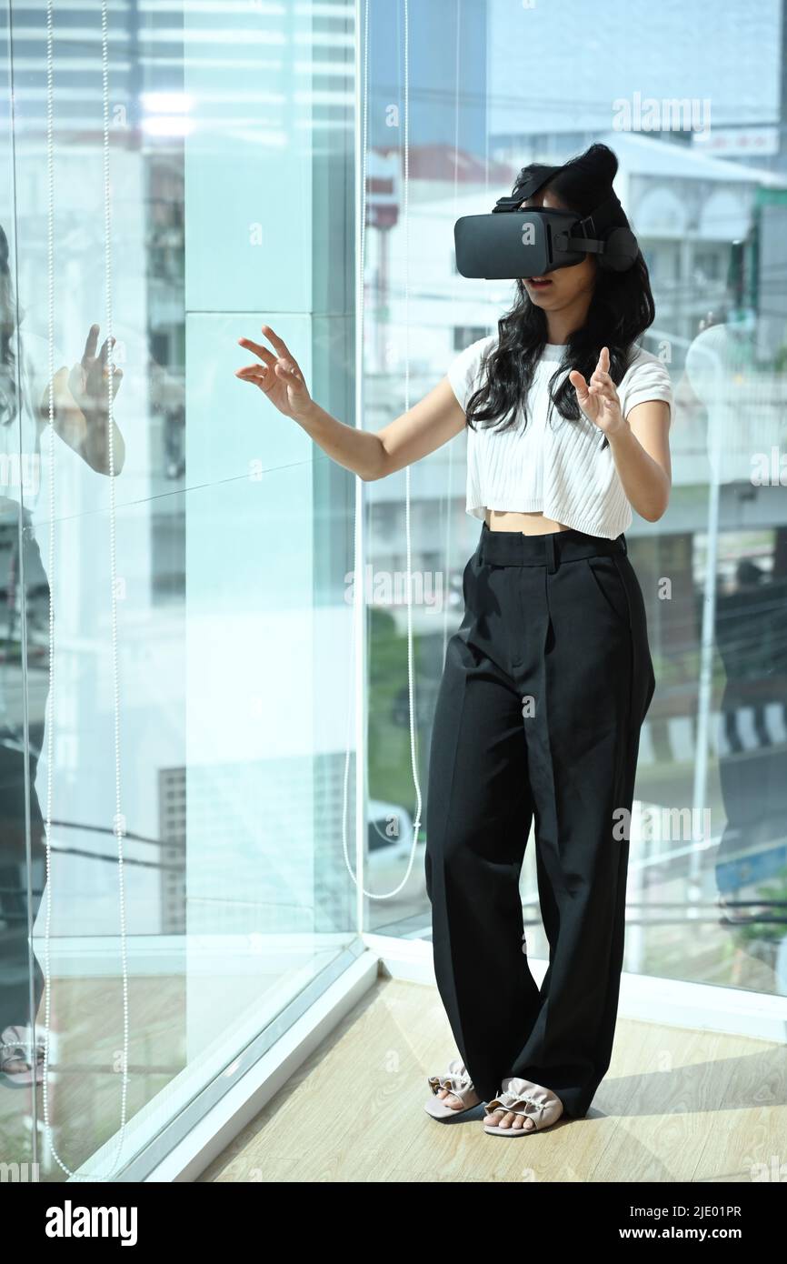 Excited young businesswoman wearing virtual reality headset and ...