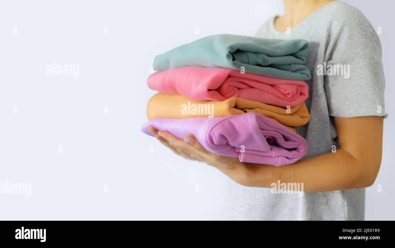 Women's hand give a stack of clothes to children's hands. Helping the ...
