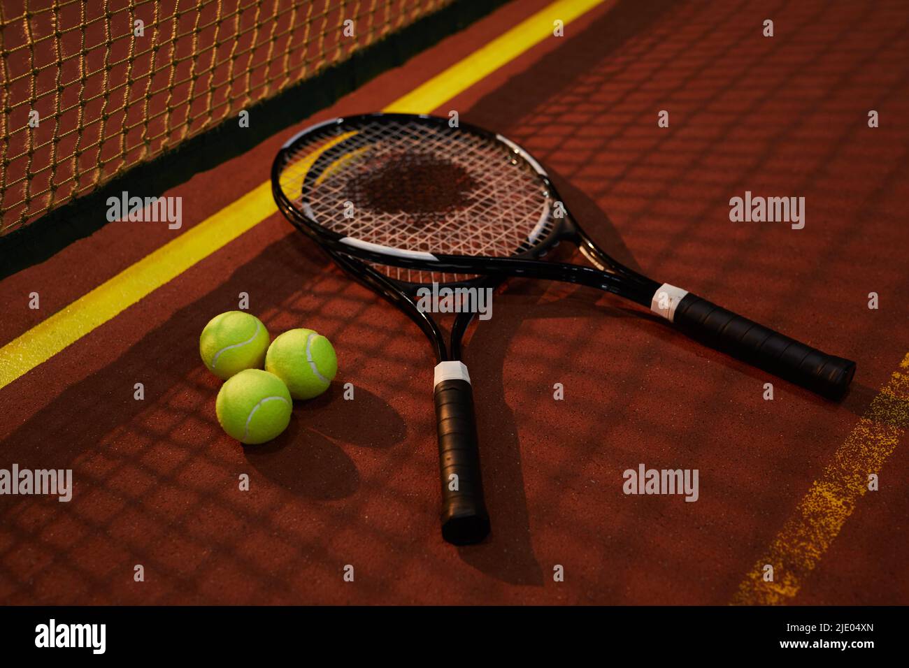 Close-up of tennis racquets of competitors and tree tennis balls lying ...