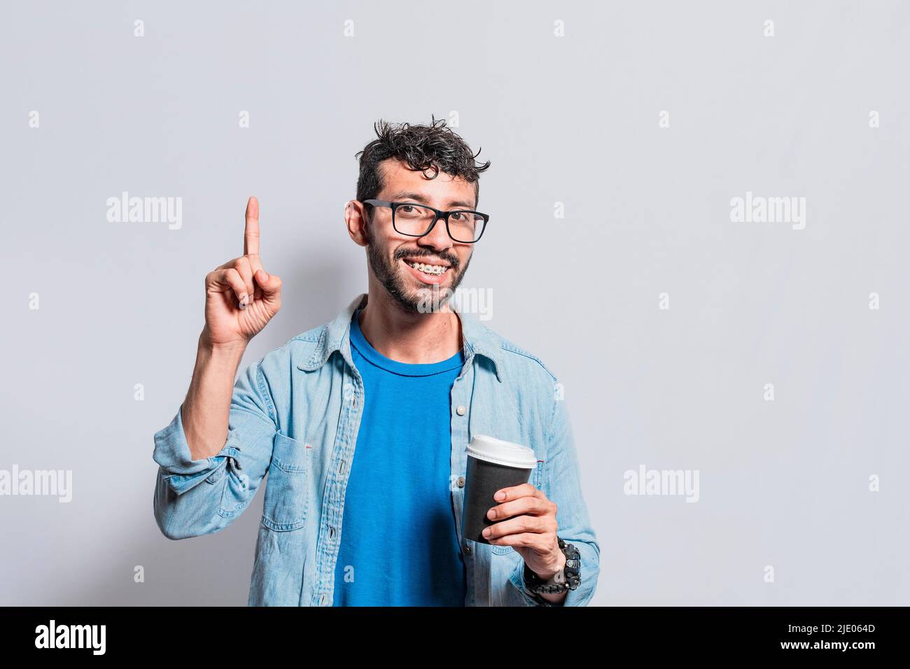 Young man with paper coffee cup pointing finger up, Happy smiling ...
