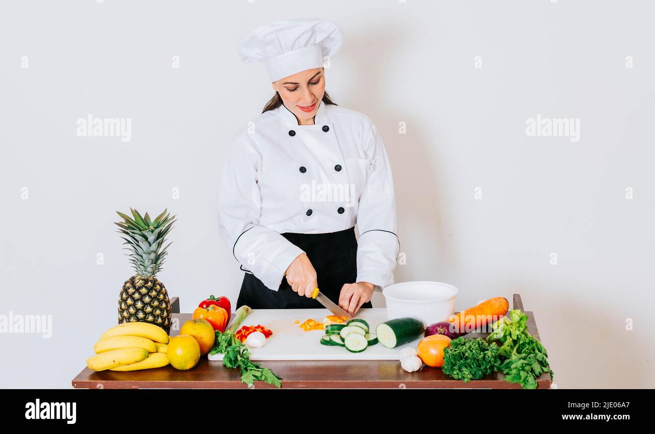 A woman chef cutting fresh vegetables, Concept of a female chef ...