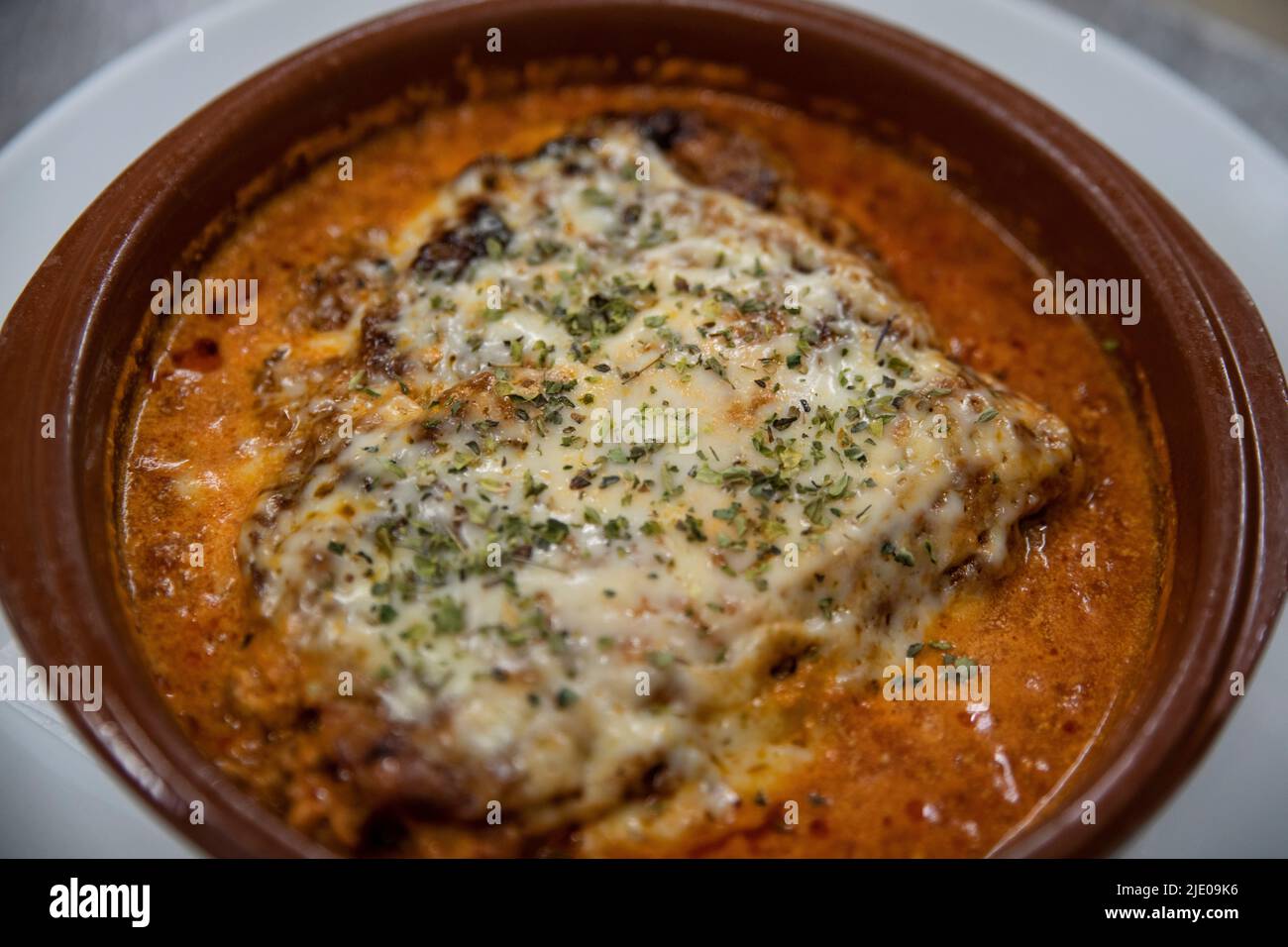 Homemade lasagna baked in a terracotta round pot, individual portion of ...