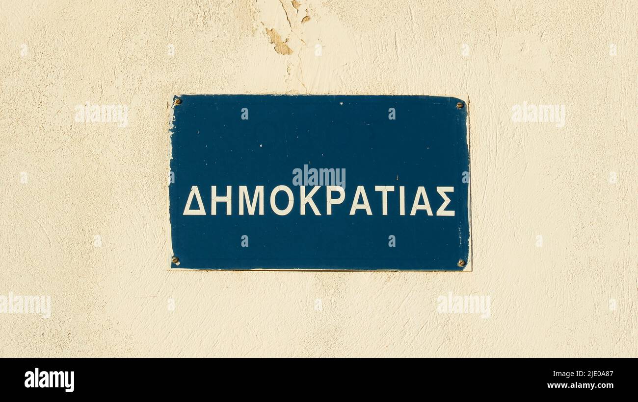 Morning light, detail, blue street sign Dimokratias on white wall ...