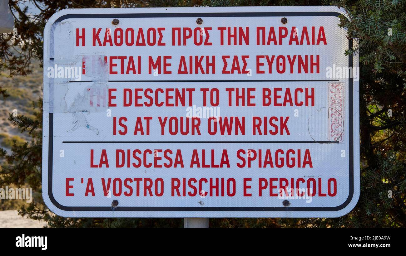 White warning sign with red writing, rocky cove, Tsigrado Beach, Milos ...