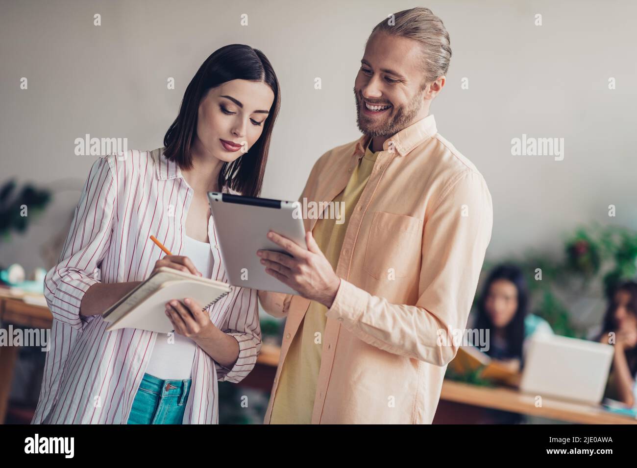 Photo of positive friendly colleagues use tablet write notes notepad ...