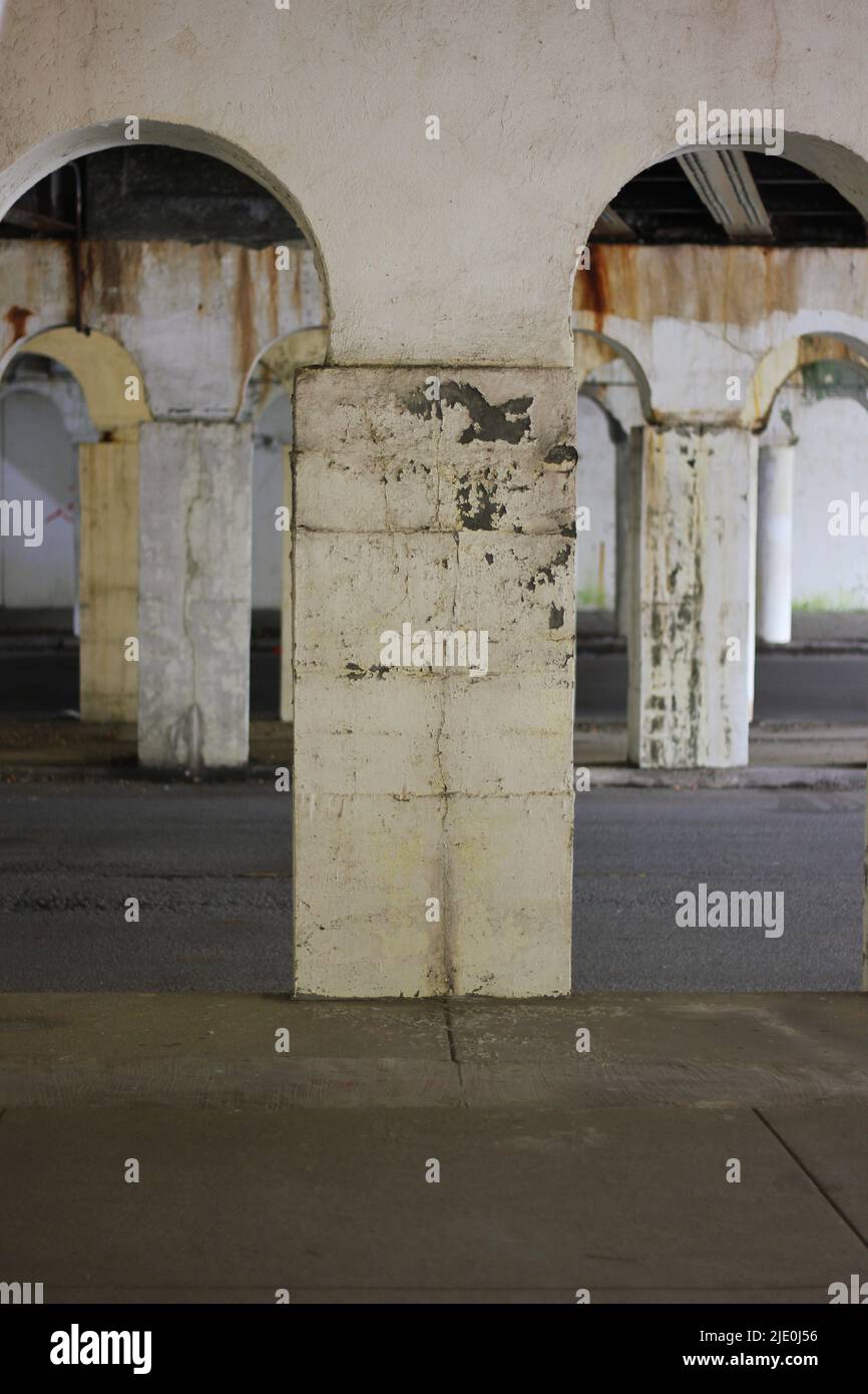 An inner city colonnade of columns holding up a bridge overhead in ...
