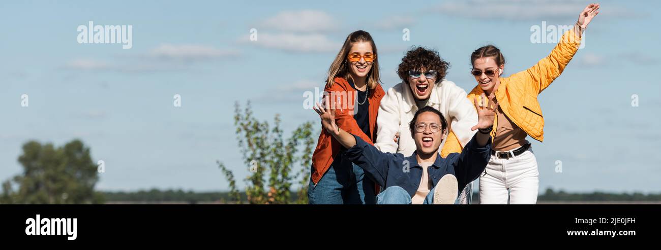 excited asian man screaming while having fun with friends outdoors ...