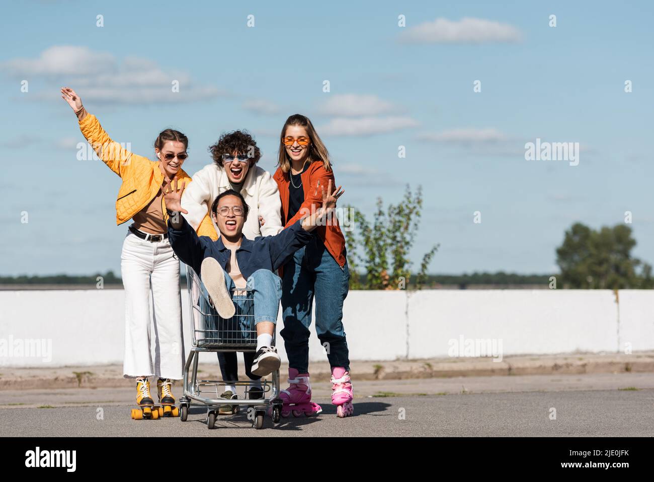 excited man shouting while moving shopping cart with asian friend near ...