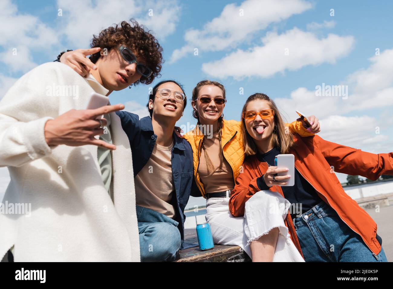 joyful multiethnic friends showing rock and victory signs while having ...