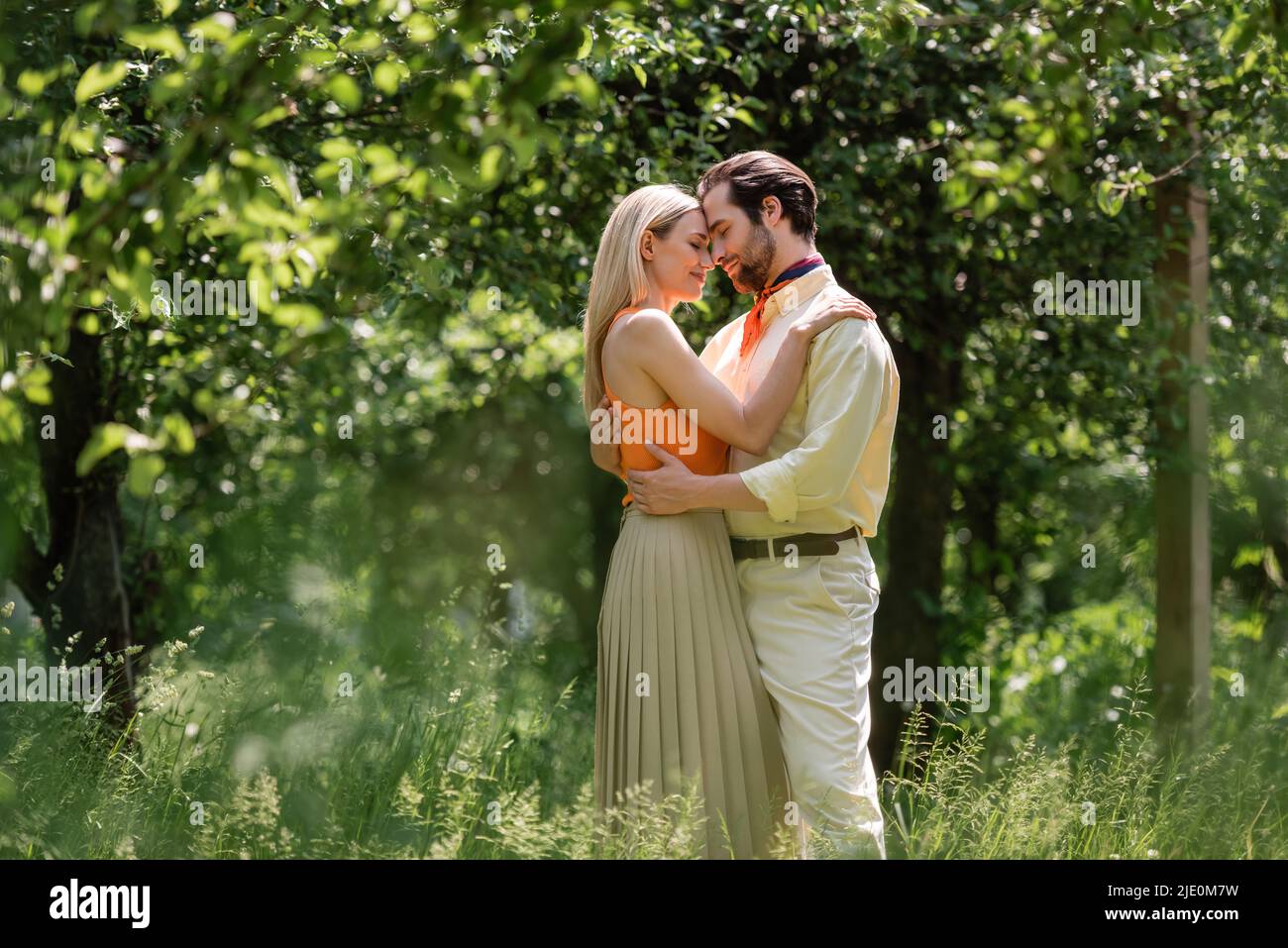 Side view of fashionable couple embracing in summer park Stock Photo ...